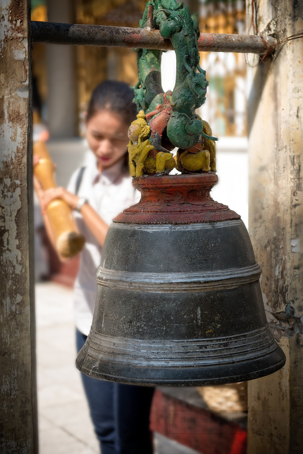 Vistor with bamboo stick hitting bell at Shwedagon Pagoda in Yan ...